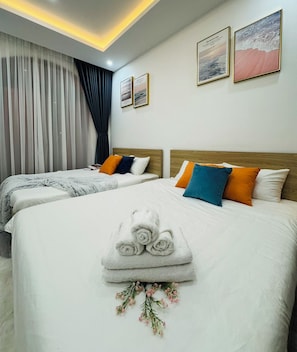 Quarto de hotel com duas camas, uma janela grande com cortinas e obras de arte nas paredes.