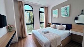 Quarto com cama, mesa de cabeceira com um vaso de flores e uma janela grande com cortinas.