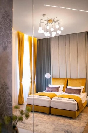 Quarto moderno com cama de casal, um lustre singular e uma janela grande com cortinas.