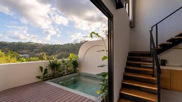 Interior moderno com escada de madeira, uma pequena piscina e vista para uma paisagem montanhosa.