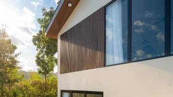 Uma casa moderna com deck de madeira, piscina e uma grande janela.