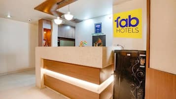 Uma área de recepção com balcão, visor digital e logotipo da Fab Hotels.