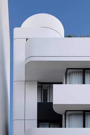 Um edifício moderno com fachada plana, grandes janelas e uma estrutura circular no topo.