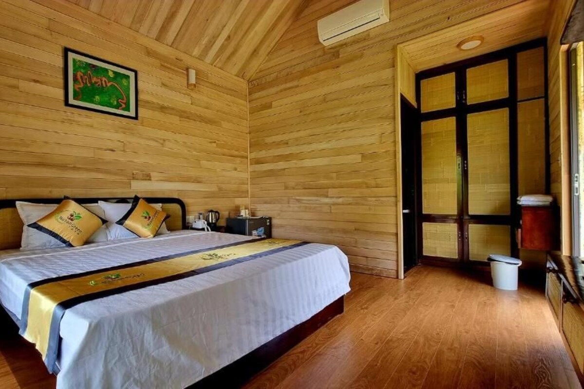 Quarto com painéis de madeira, uma cama, mesa de cabeceira, ar condicionado fixado na parede e uma porta com design tradicional.
