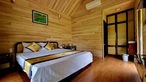 Quarto com painéis de madeira, uma cama, mesa de cabeceira, ar condicionado fixado na parede e uma porta com design tradicional.