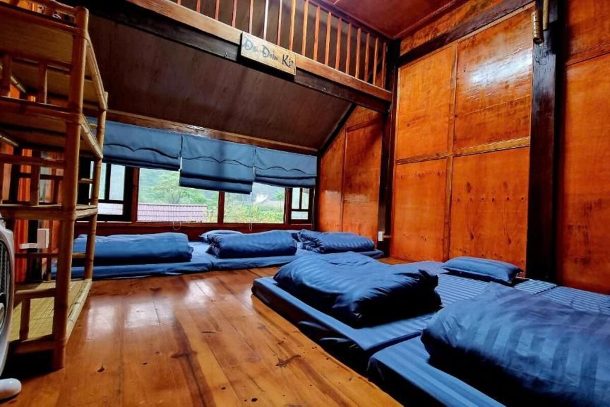 Quarto com beliches, paredes de madeira e janela com vista.
