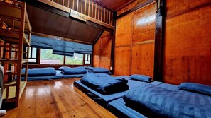 Quarto com beliches, paredes de madeira e janela com vista.