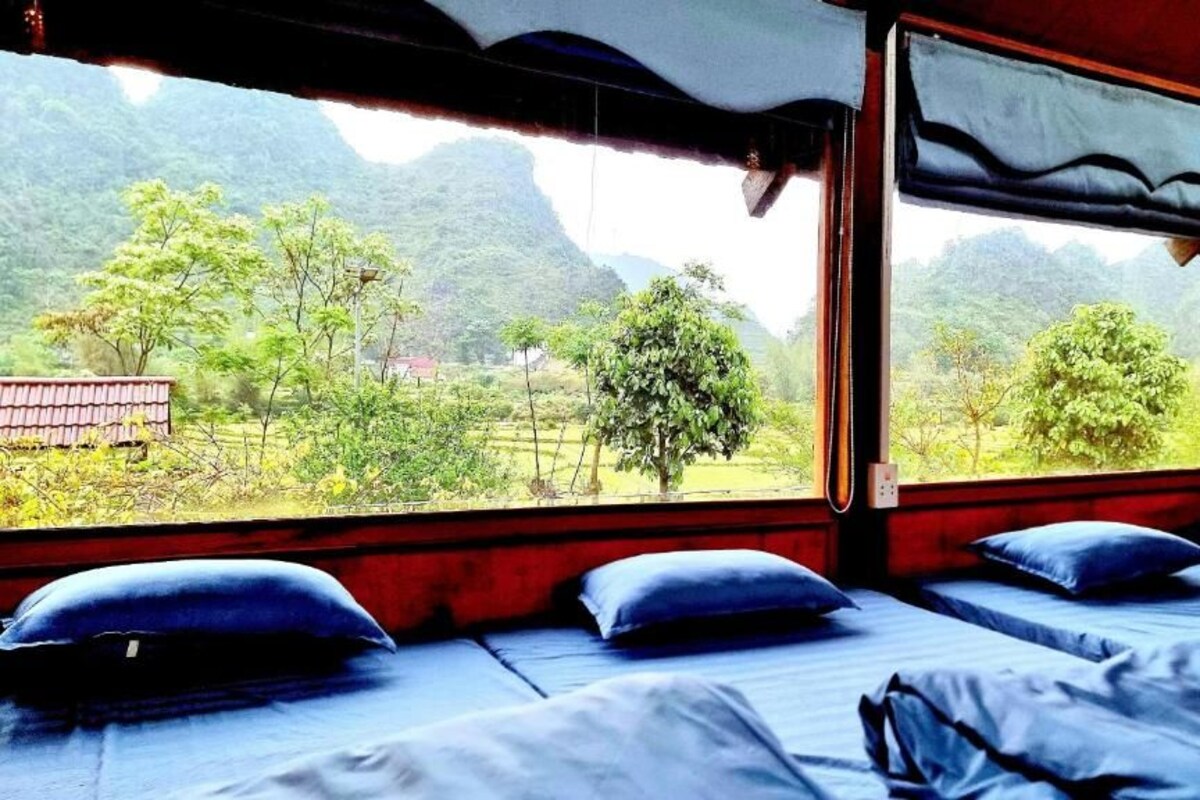 Quarto com cama e janela com vista para uma paisagem montanhosa.