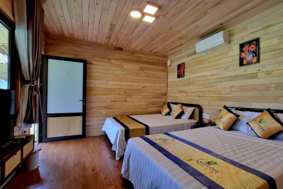 Quarto com duas camas, paredes de madeira e uma porta.