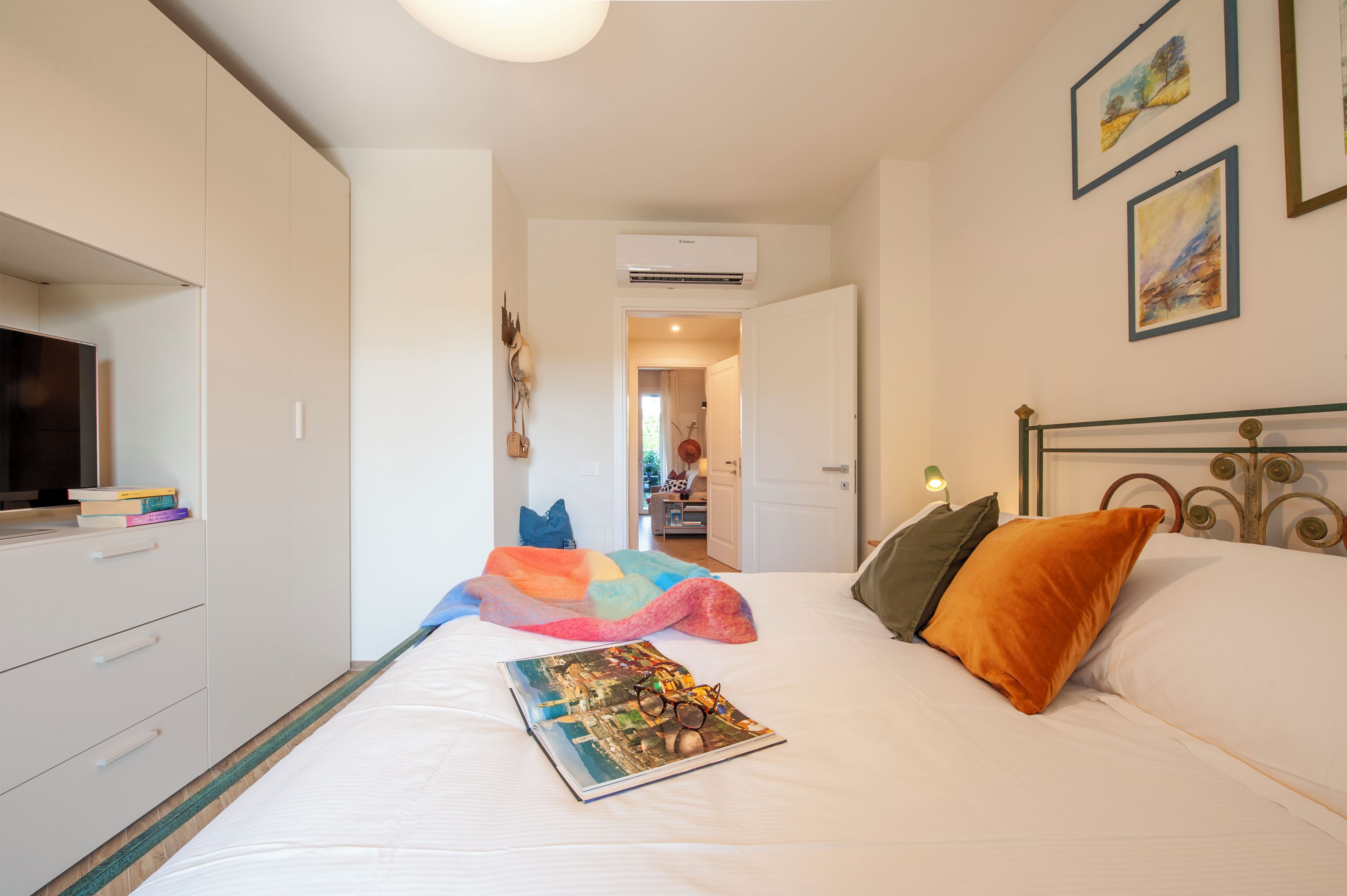 Quarto com cama, escrivaninha com computador, guarda-roupa e porta que dá para outro espaço.