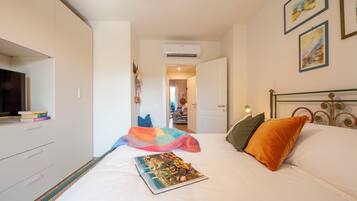 Quarto com cama, escrivaninha com computador, guarda-roupa e porta que dá para outro espaço.