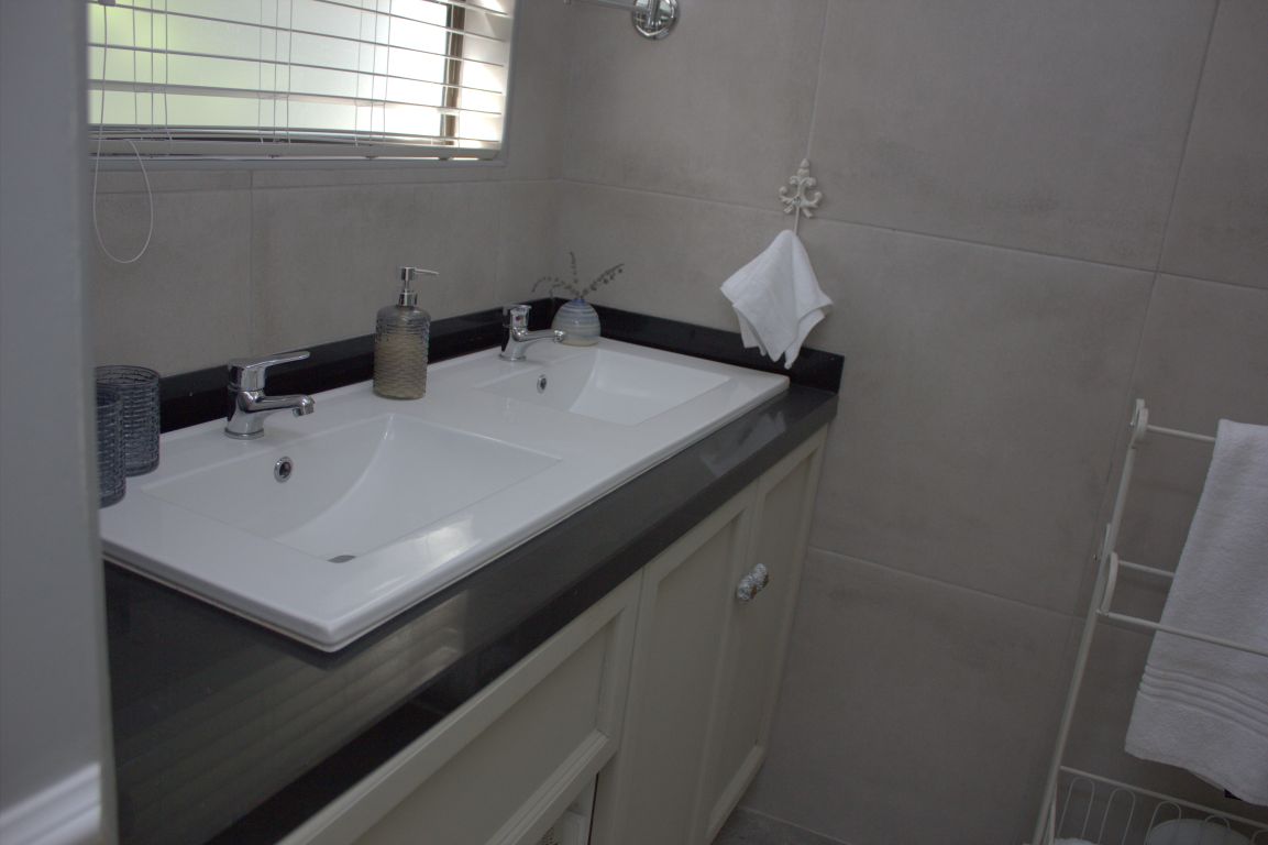 Casa de banho com lavatório branco, bancada preta e suporte para toalhas.