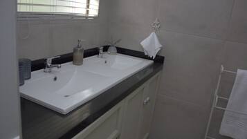 Casa de banho com lavatório branco, bancada preta e suporte para toalhas.