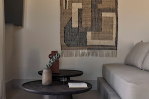 Uma sala de estar moderna com uma mesa redonda, um sofá e um tapeçário na parede.
