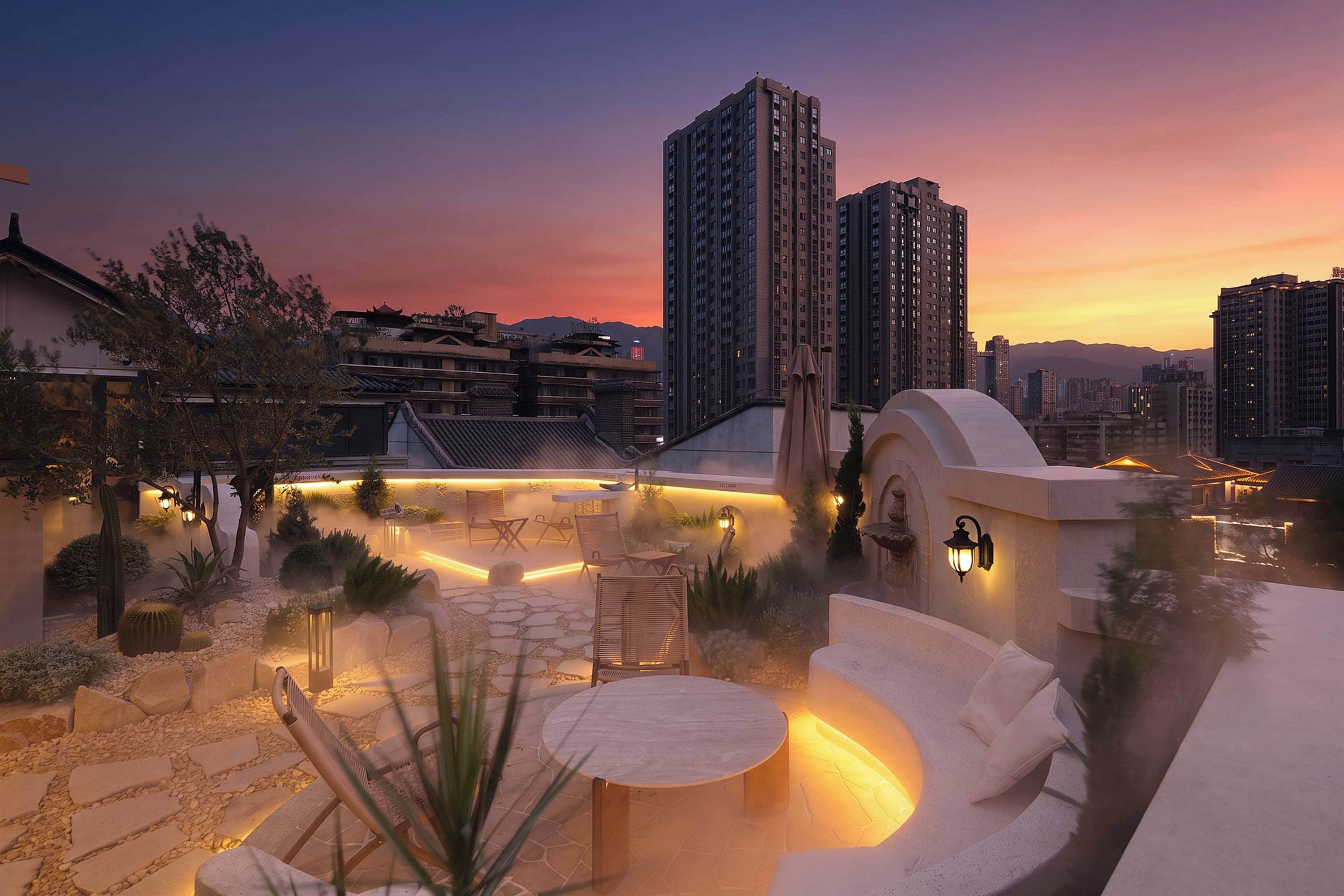 Jardim no terraço com áreas de estar, um espelho d'água e vista para edif ícios altos ao pôr do sol.