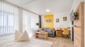 Quarto de hotel com cama, sofá, escrivaninha e televisão.