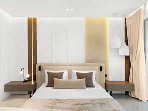 Quarto moderno com cama grande, mesas de cabeceira e luminária na parede.