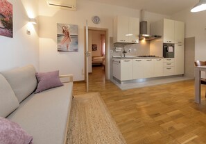 Cozinha moderna com ilha central, piso de madeira e área de refeições com mesa e cadeiras.