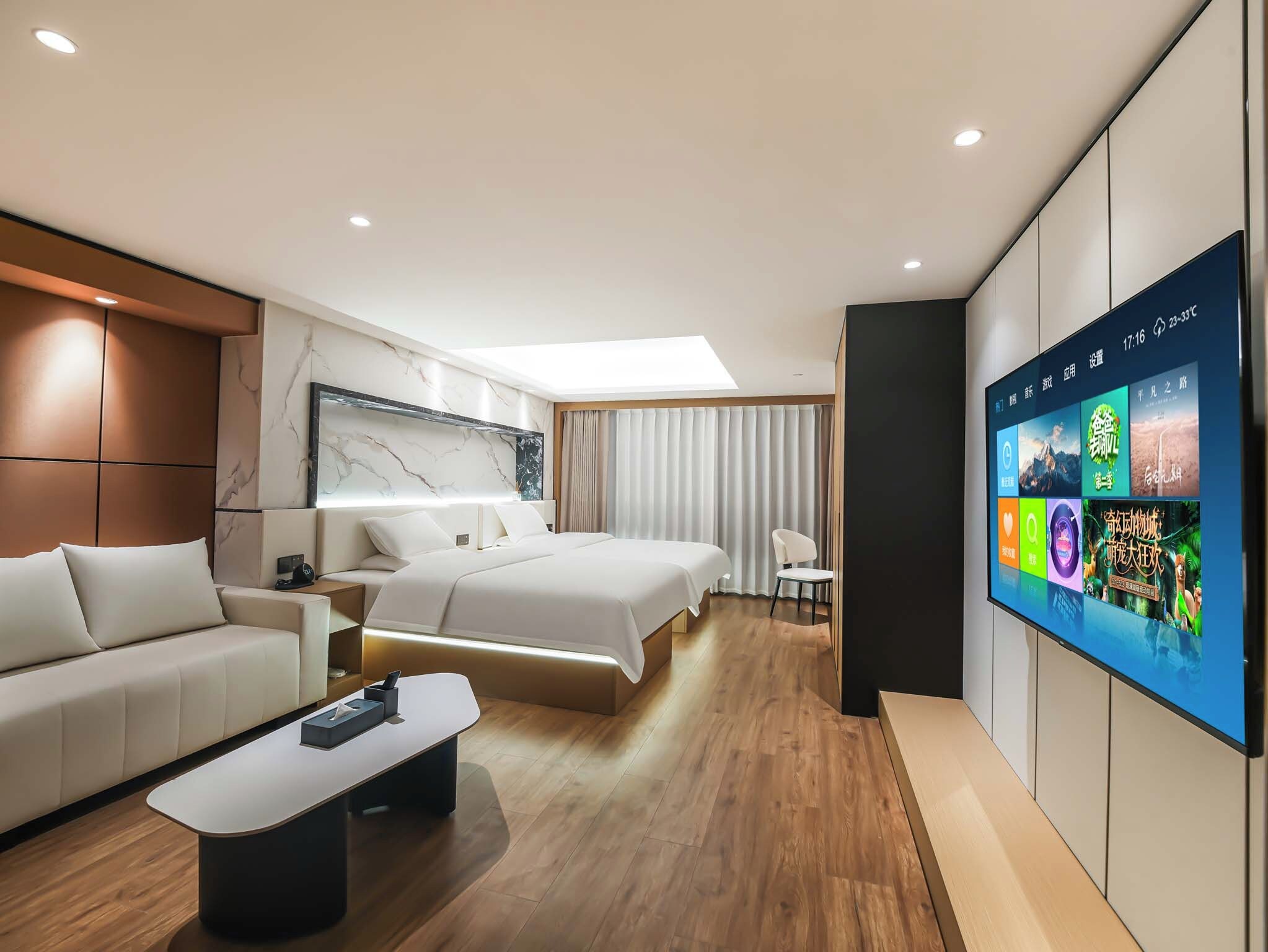 Quarto de hotel moderno com cama, sofá, televisão e escrivaninha.