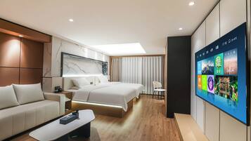 Quarto de hotel moderno com cama, sofá, televisão e escrivaninha.