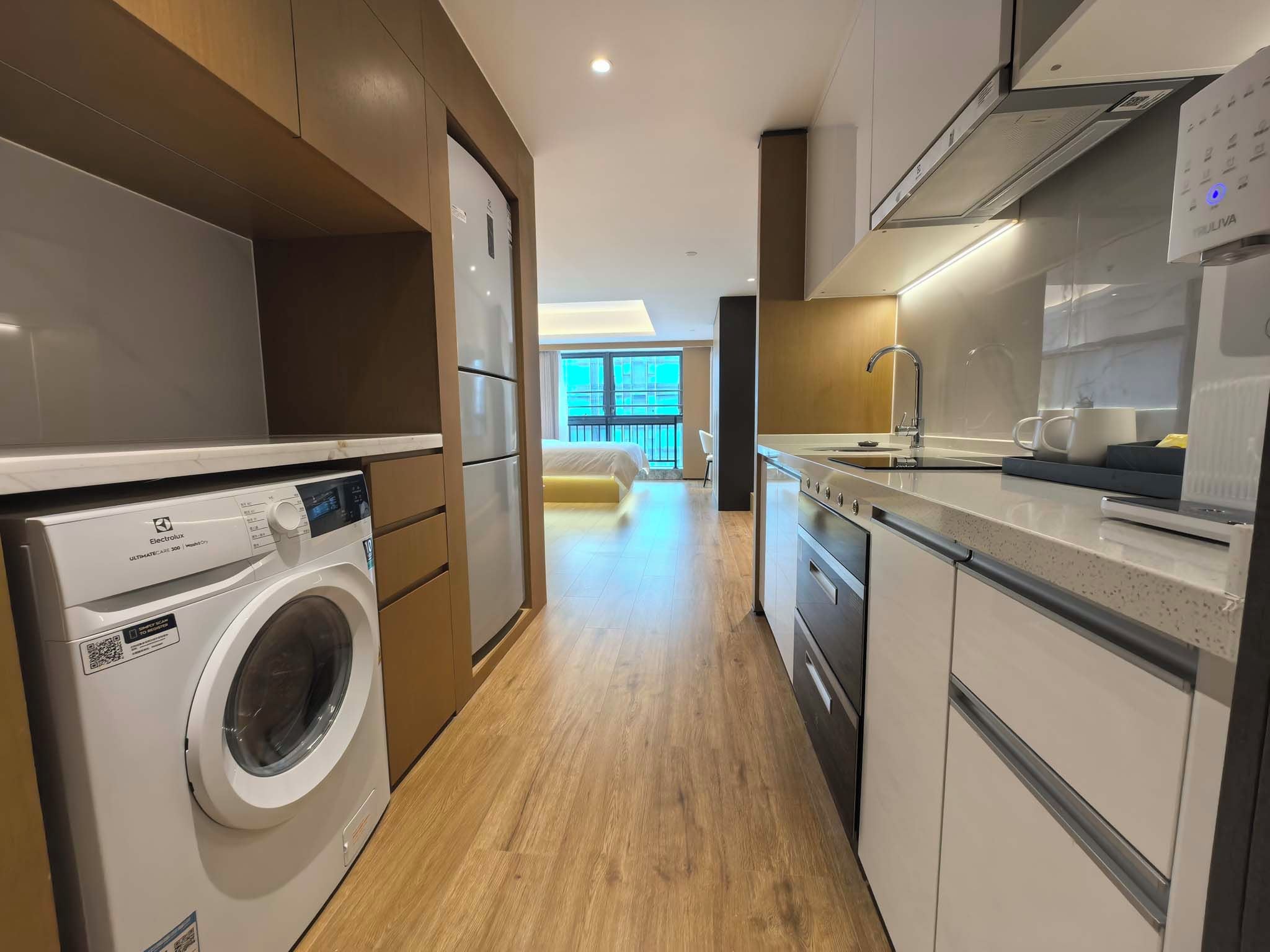 Cozinha moderna com máquina de lavar embutida, espaço de refeições e vista para uma varanda.