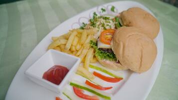 Um prato com um hambúrguer, batatas fritas e uma pequena tigela de ketchup.