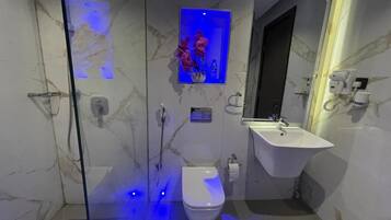 Uma casa de banho moderna com chuveiro em cabine de vidro, sanita branca e toucador com lavatório.