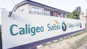 Placa de Caligeo Suites com um edifício moderno ao fundo.
