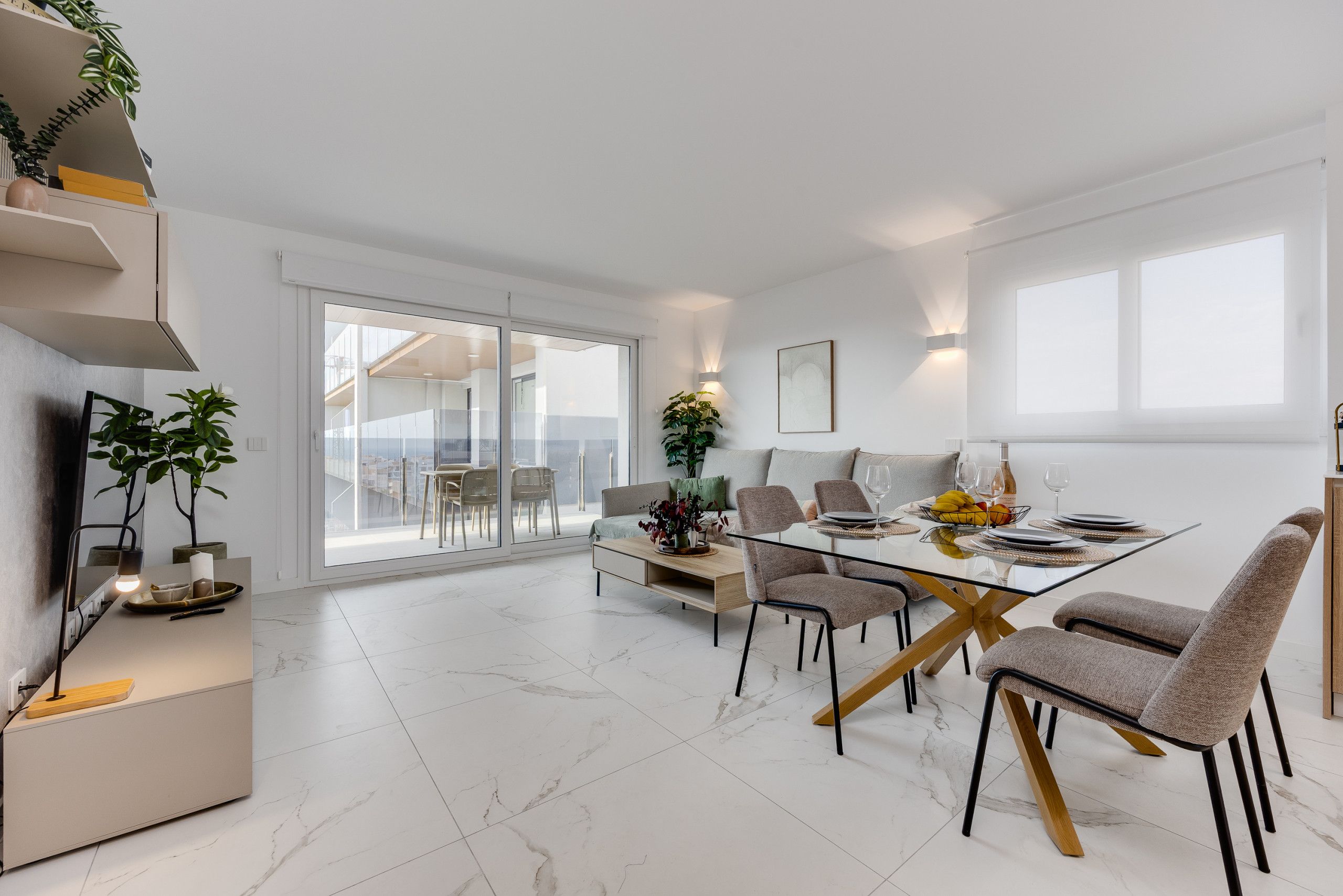 Uma área de jantar moderna com mesa de vidro, cadeiras e vista da cidade por grandes janelas.