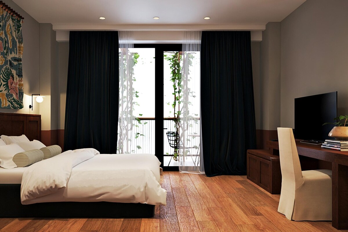 Quarto moderno com cama, escrivaninha, televisão e uma grande janela com cortinas.