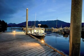 Um barco atracado em um cais, com montanhas ao fundo.