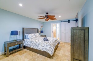Quarto com cama, mesas de cabeceira, ventoinha no teto e guarda-roupa.