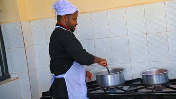 Uma pessoa cozinhando em uma cozinha com fogão a gás e várias panelas.