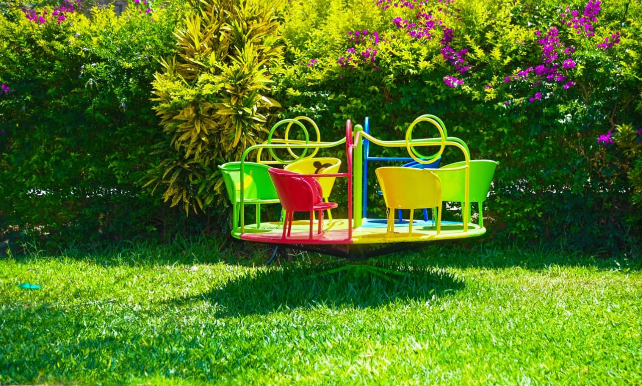 Um baloiço ao ar livre colorido num jardim exuberante, cheio de folhagem densa e plantas floridas.