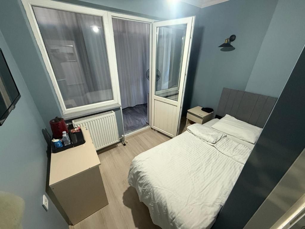 Quarto com cama, escrivaninha, cadeira, janela e radiador.