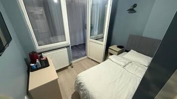 Quarto com cama, escrivaninha, cadeira, janela e radiador.