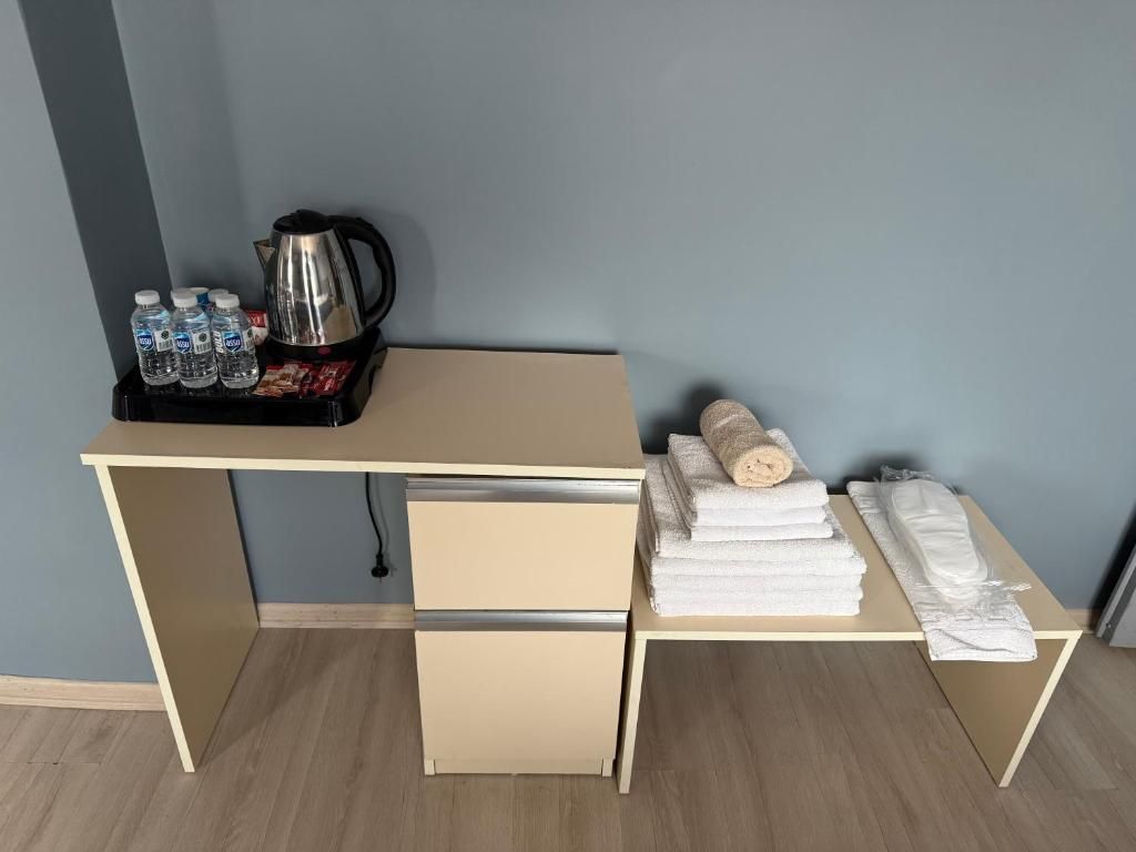 Quarto compacto com escrivaninha, chaleira, água engarrafada e toalhas dobradas com cuidado.