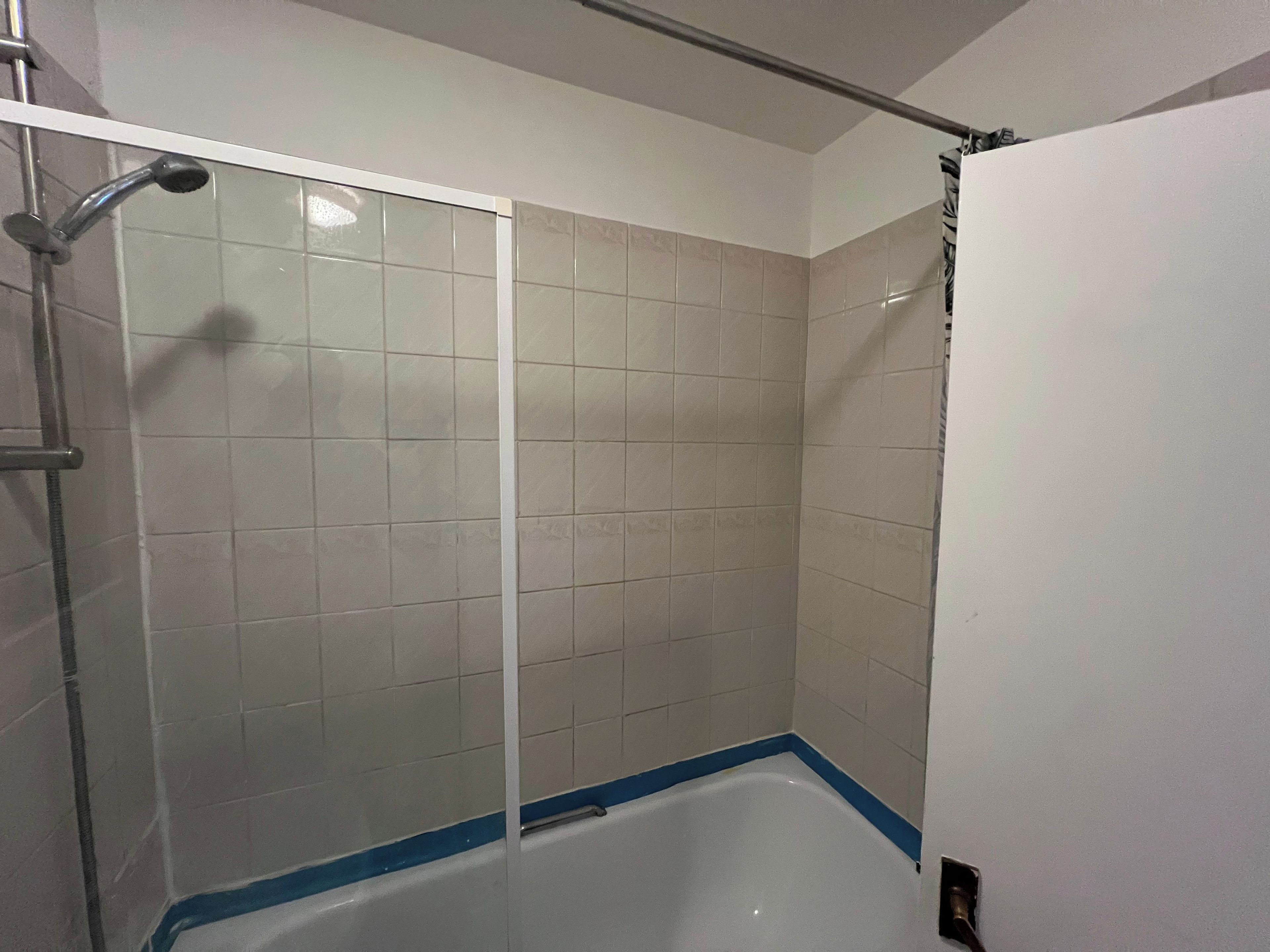 Casa de banho com chuveiro, banheira e paredes revestidas de azulejos.