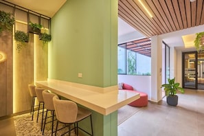 Espaço moderno com área de bar, assentos e um vaso de planta.