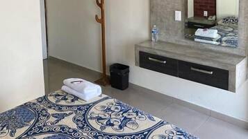 Quarto com cama, porta-roupas de madeira, penteadeira com espelho e aparelho de ar condicionado.