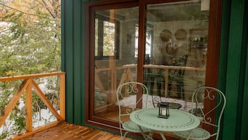 Um deck de madeira com uma porta de vidro que dá para um quarto com mesa e cadeiras.