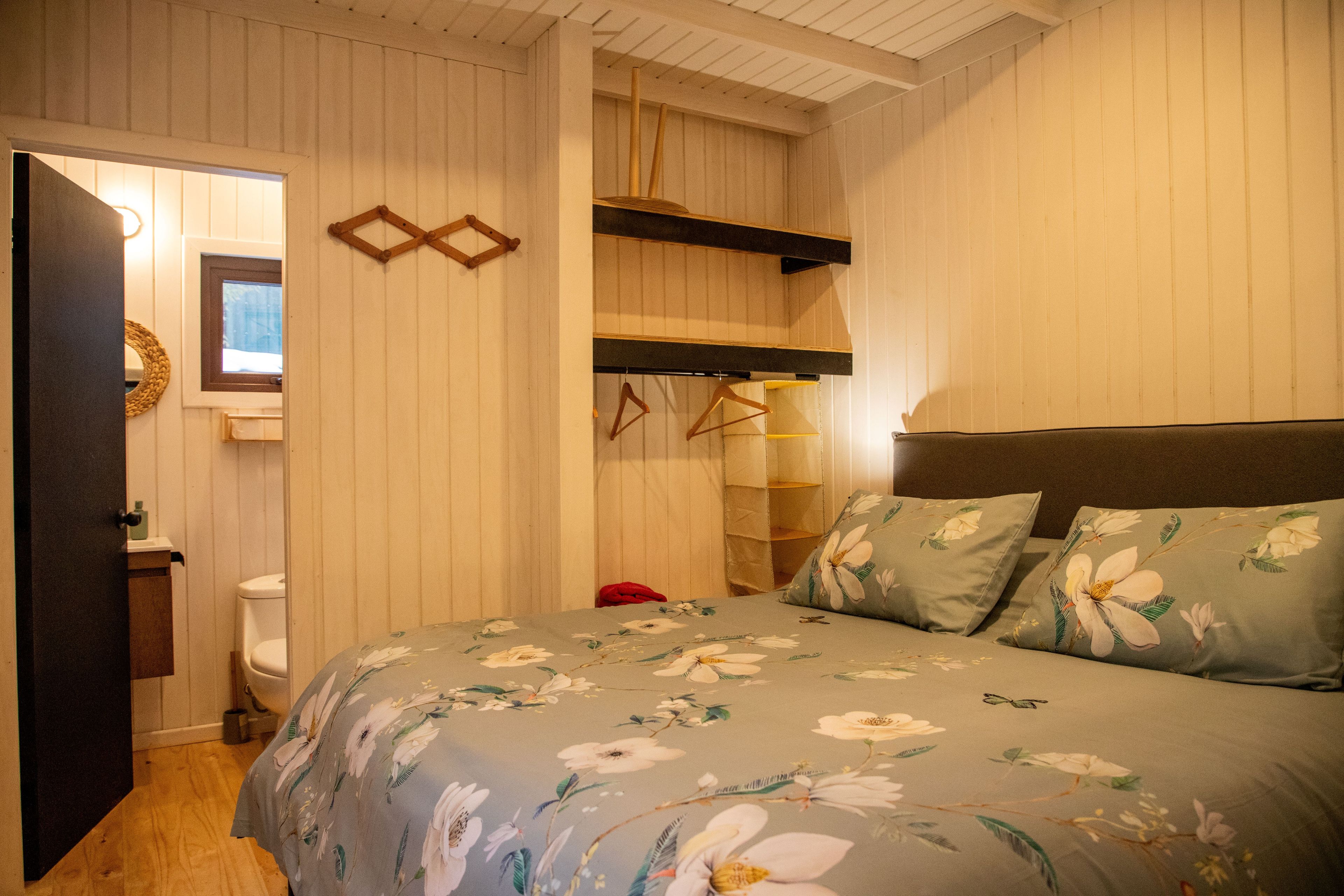 Quarto com cama, um cabideiro e teto de madeira.