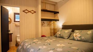 Quarto com cama, um cabideiro e teto de madeira.