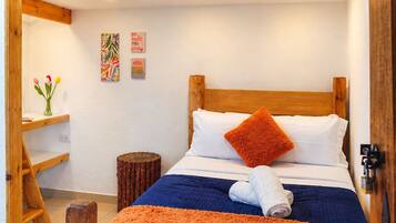 Uma cama beliche com estrutura de madeira, edredom azul e laranja, e travesseiro branco.