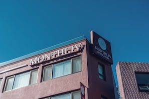 Um edifício com uma placa que diz 'ESTADIA MENSAL NO HOTEL'.