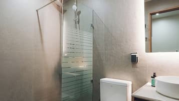 Uma casa de banho moderna com cabine de duche em vidro, sanita e lavatório.