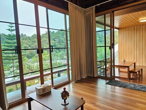 Quarto com grandes portas de vidro deslizantes, uma mesa de madeira e um banco.