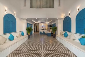 Uma área de recepção de hotel com piso estampado, assentos acolchoados e um balcão de atendimento.