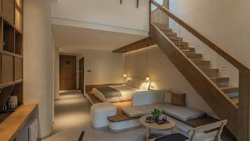 Um interior moderno com escada, sofá, mesa de centro e estante.