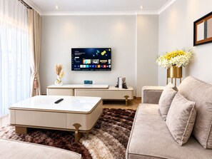 Uma sala de estar moderna com televisão de tela plana, um sofá, uma mesa de centro e um vaso decorativo com flores.